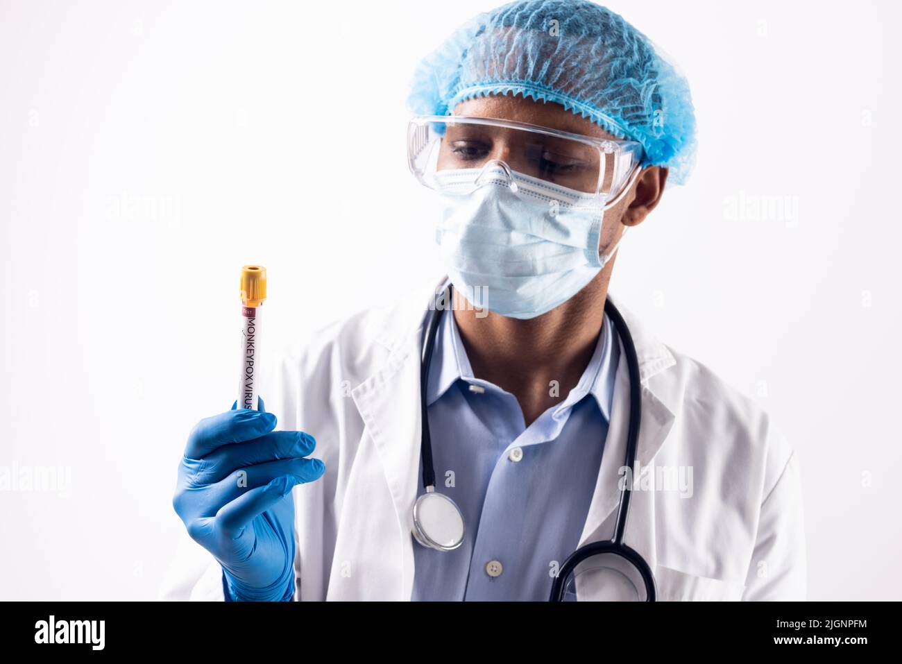 African american male doctor wearing face mask, holding vial with ...