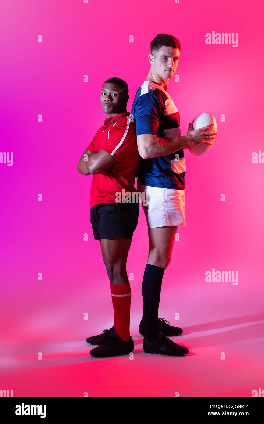 Portrait of diverse male rugby players with rugby ball over pink ...