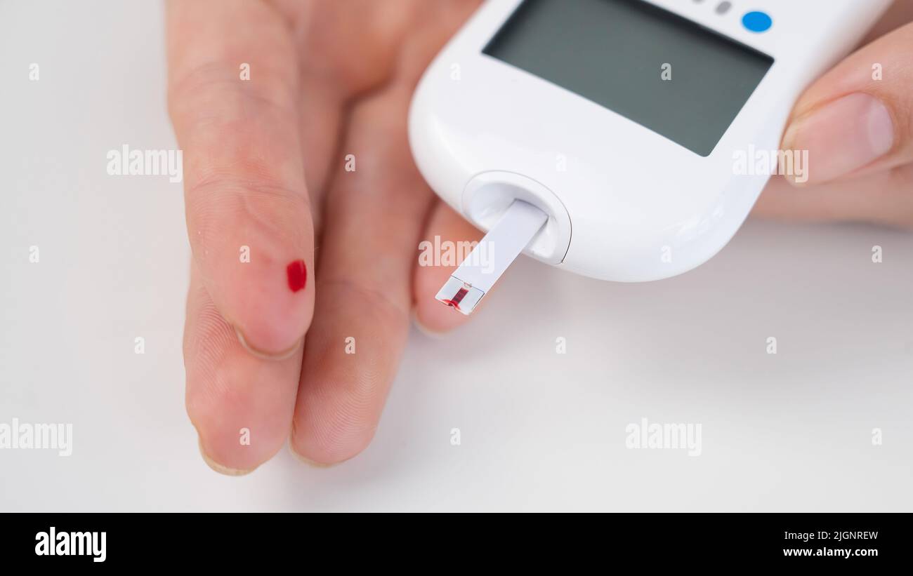 Woman measures blood sugar level with a glucometer Stock Photo - Alamy