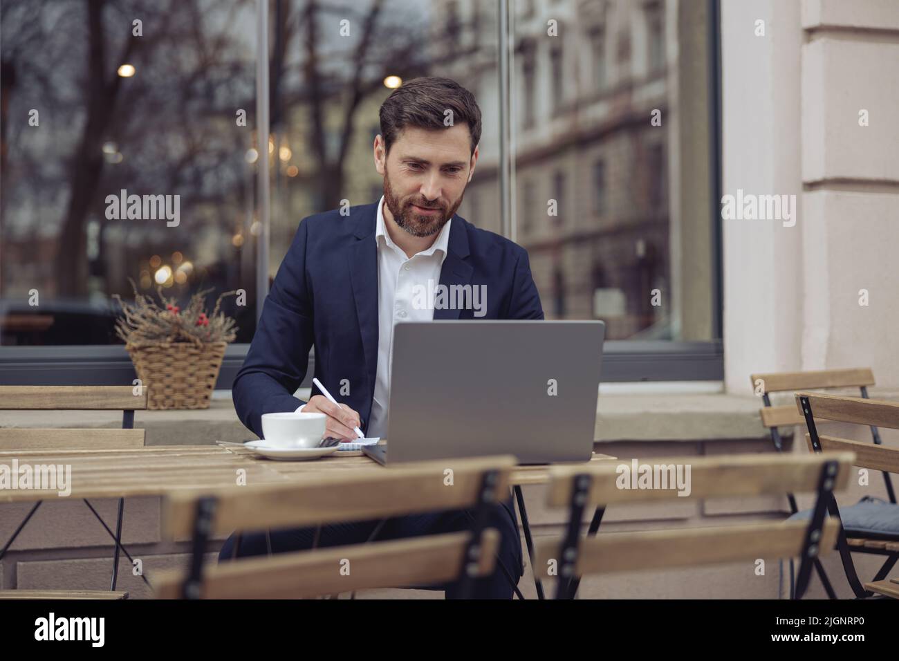 Caucasian young elegant male writer working at laptop in cafeteria and ...