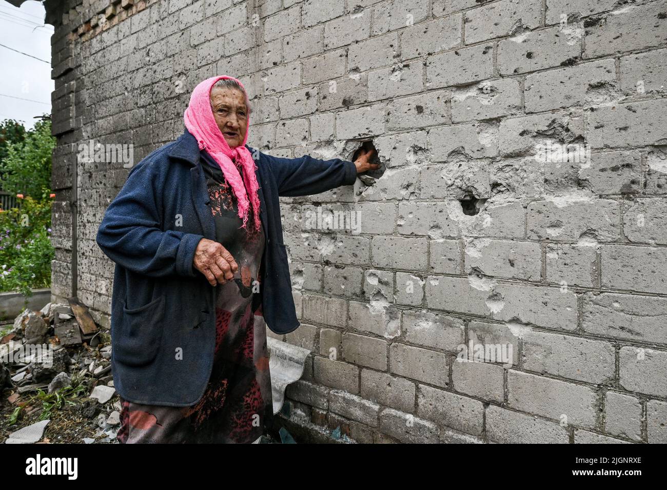 An elderly woman is seen outside her house damaged by the russian ...