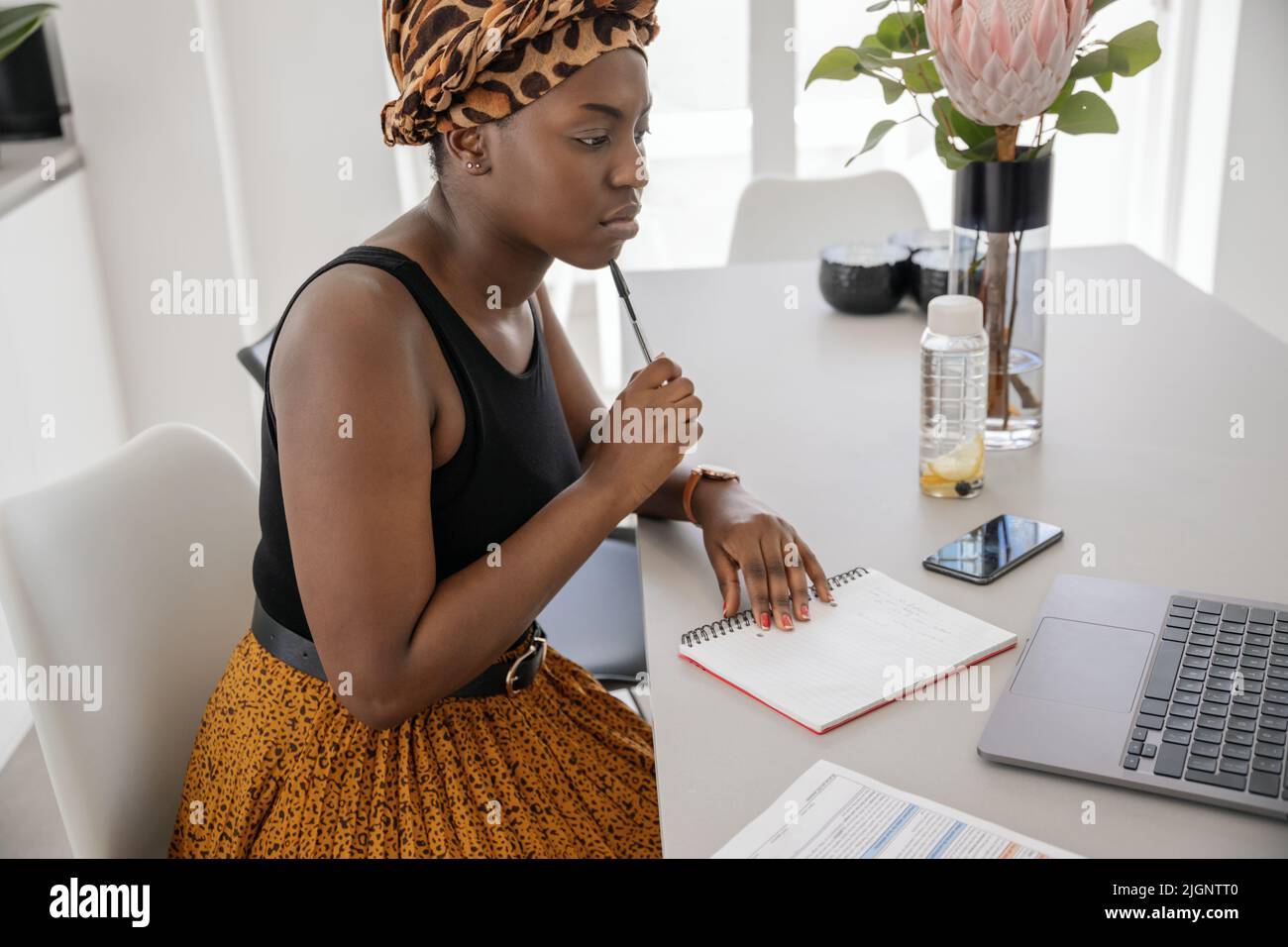 Black African woman working from home, going through paperwork. Laptop ...