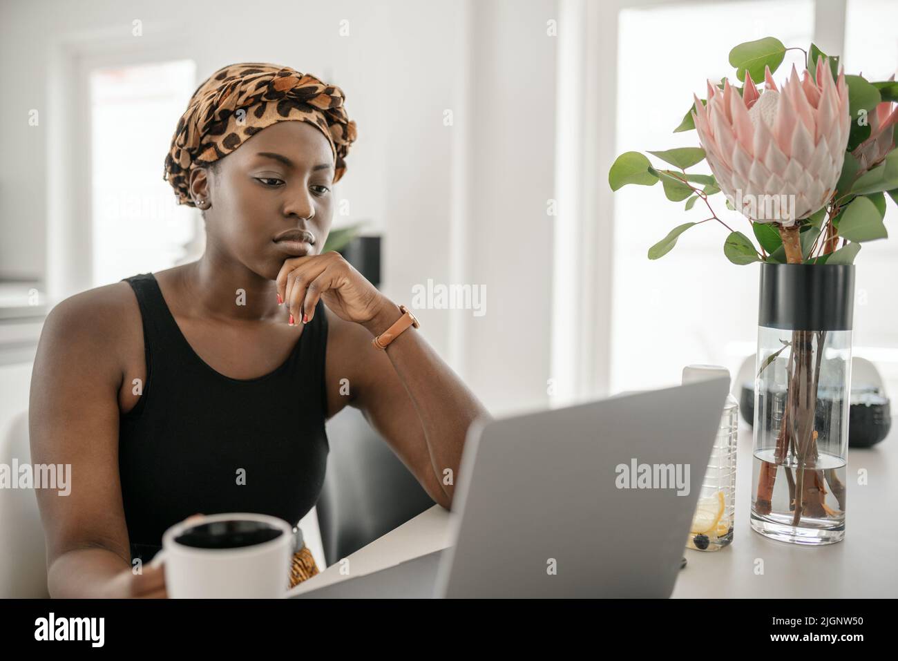 Black African woman working from home, looking at laptop. Laptop and ...