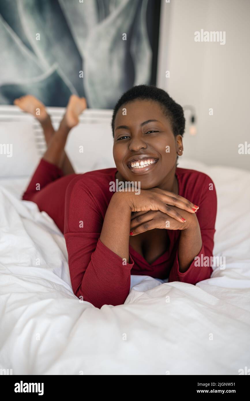 Close up portrait of beautiful African woman laying on bed with legs ...