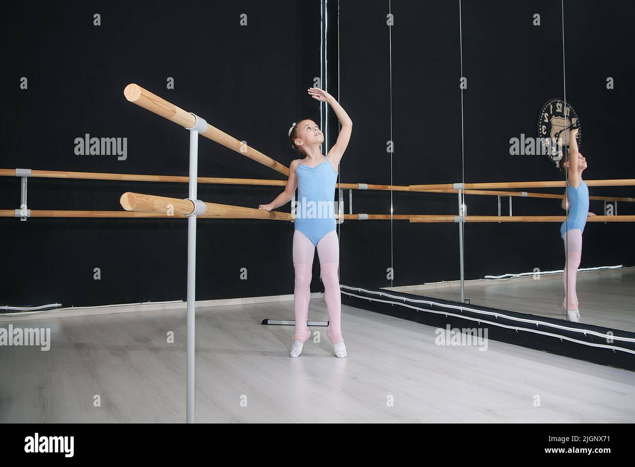 little girl does exercises in the hall of the choreographic school with ...