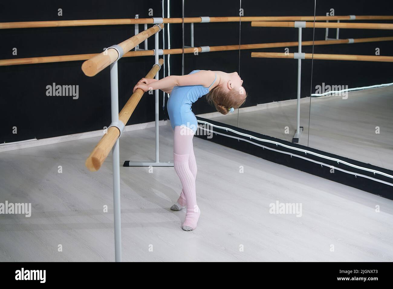 little girl does exercises in the hall of the choreographic school with ...