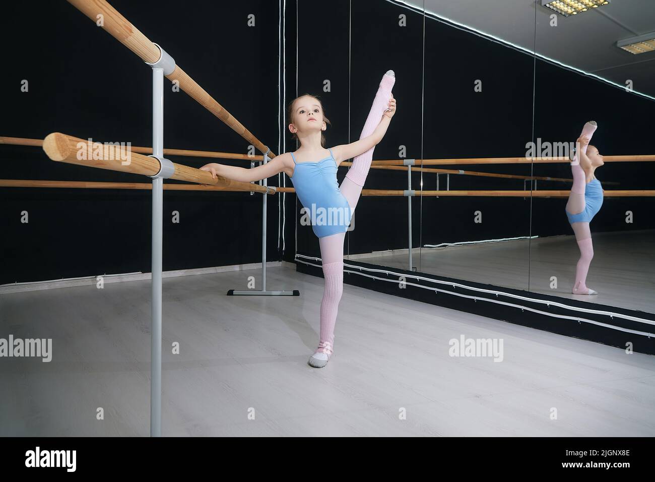 little girl does exercises in the hall of the choreographic school with ...
