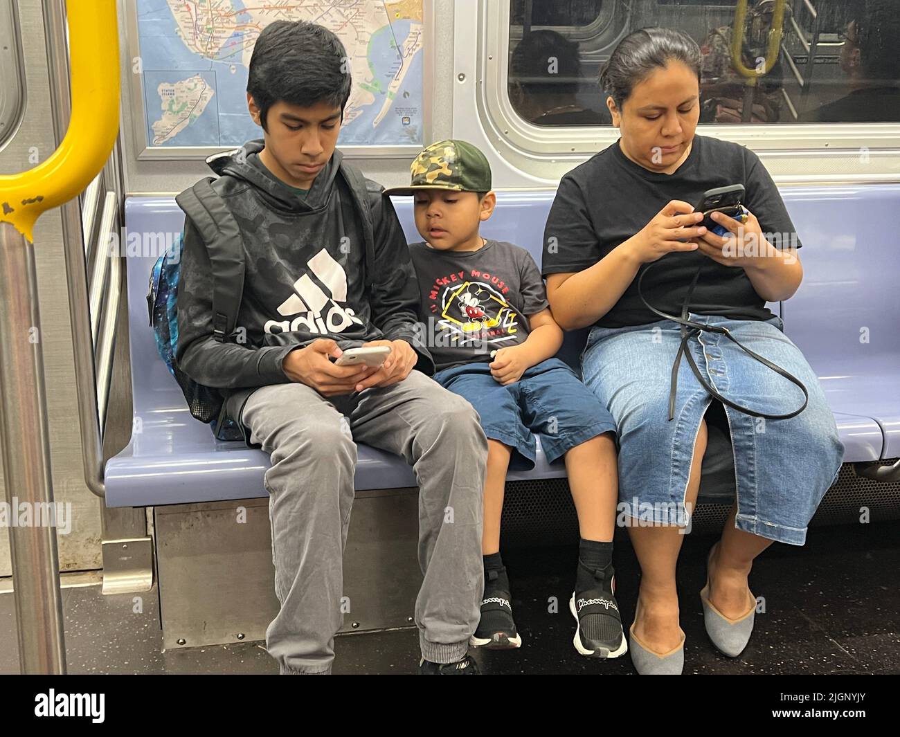 Mom and kids occupy themselves with their phones while riding an NYC ...
