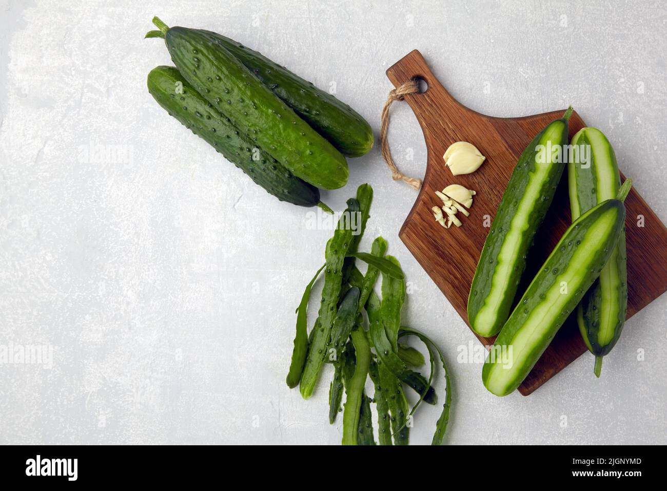 Fresh cucumbers with skin and knife on a brown wooden cutting board on ...