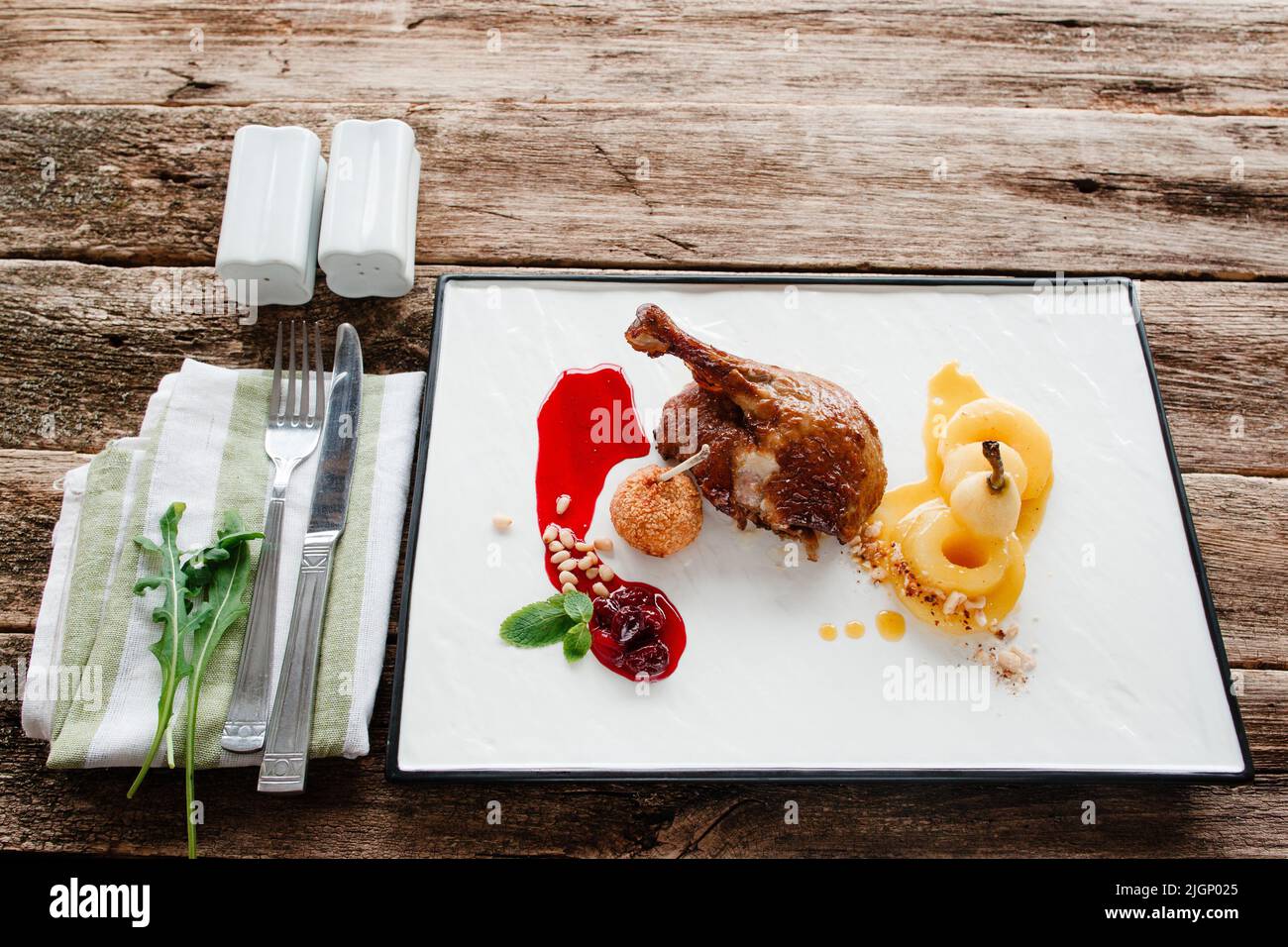 Roasted duck leg with pear and cutlery Stock Photo - Alamy