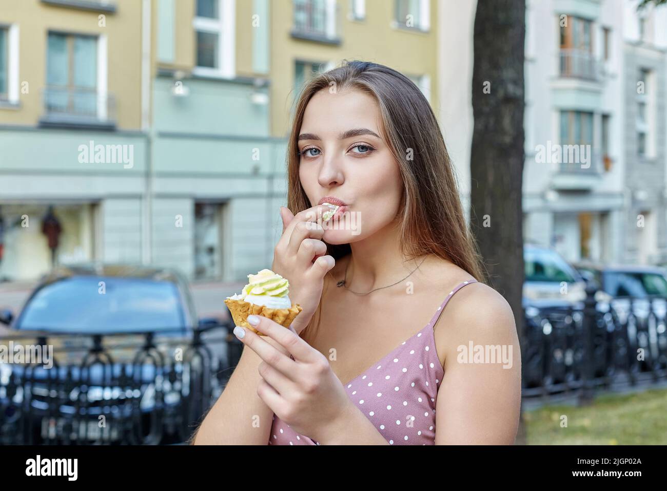 attractive girl holds a cake in her hands and holds her finger in her ...