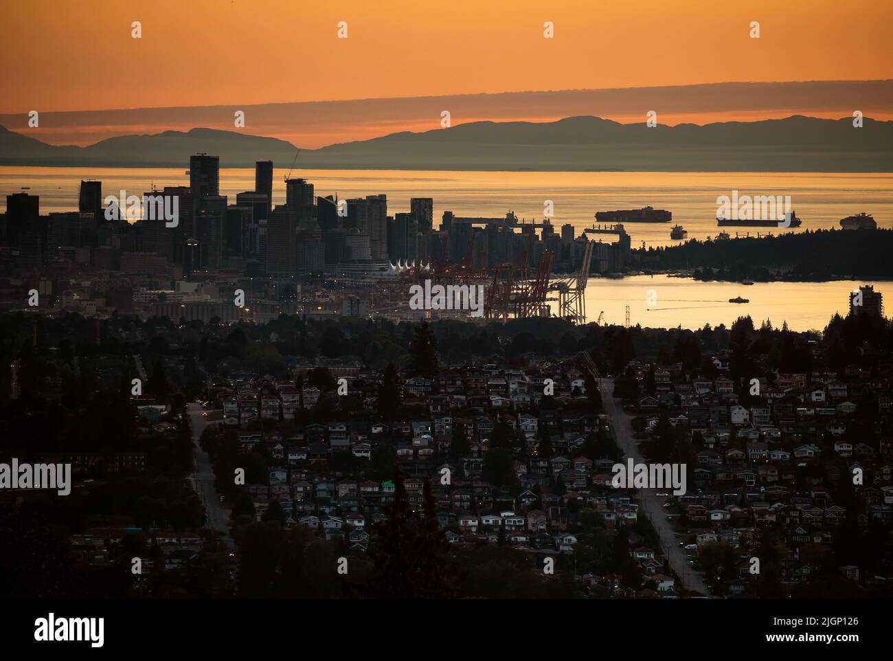 A Seabus passenger ferry, right, travels across Burrard Inlet at sunset ...
