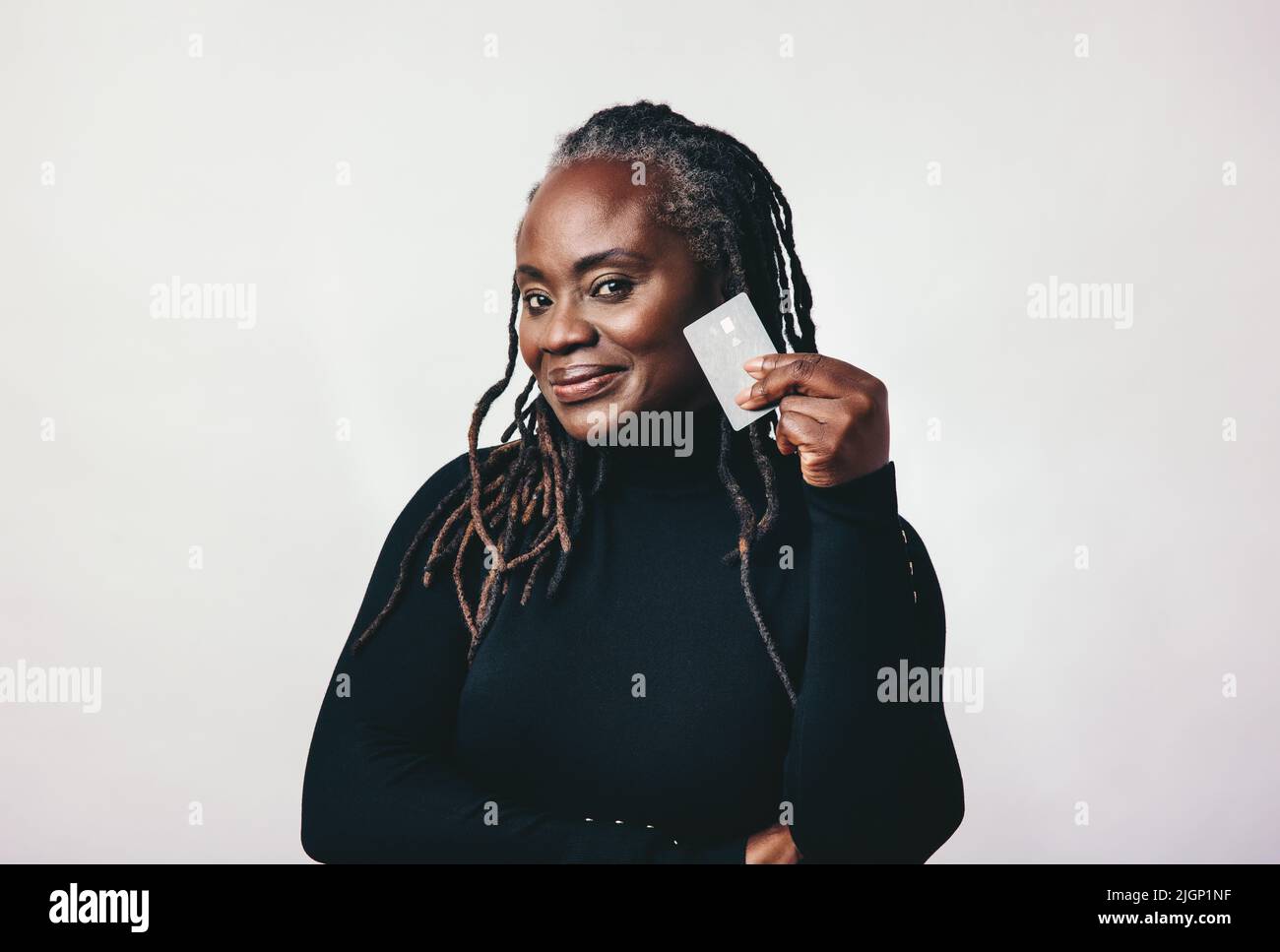 Mature woman with dreadlocks looking at the camera while holding a ...