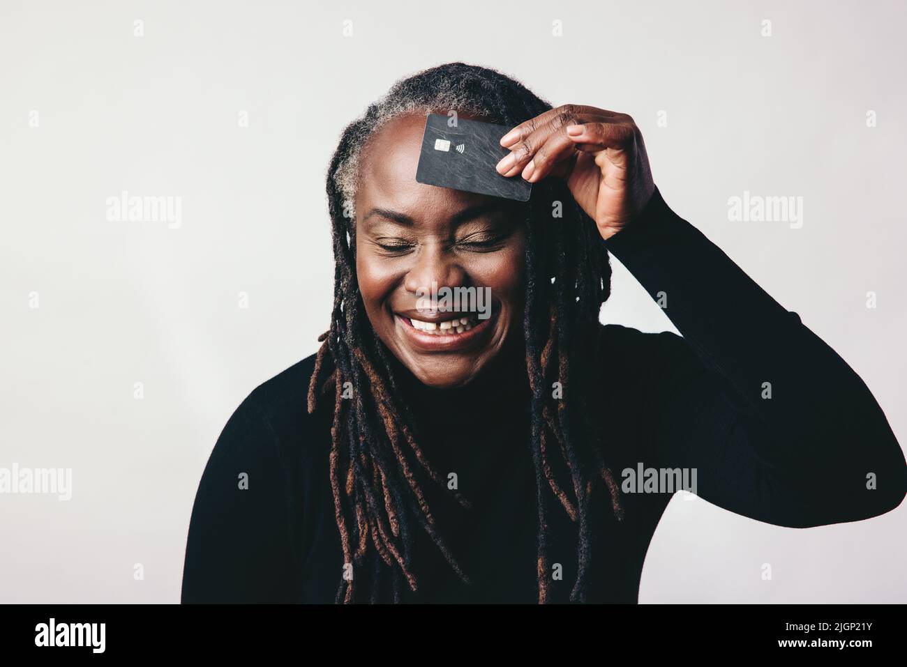 Cheerful mature woman with dreadlocks smiling happily while holding a ...