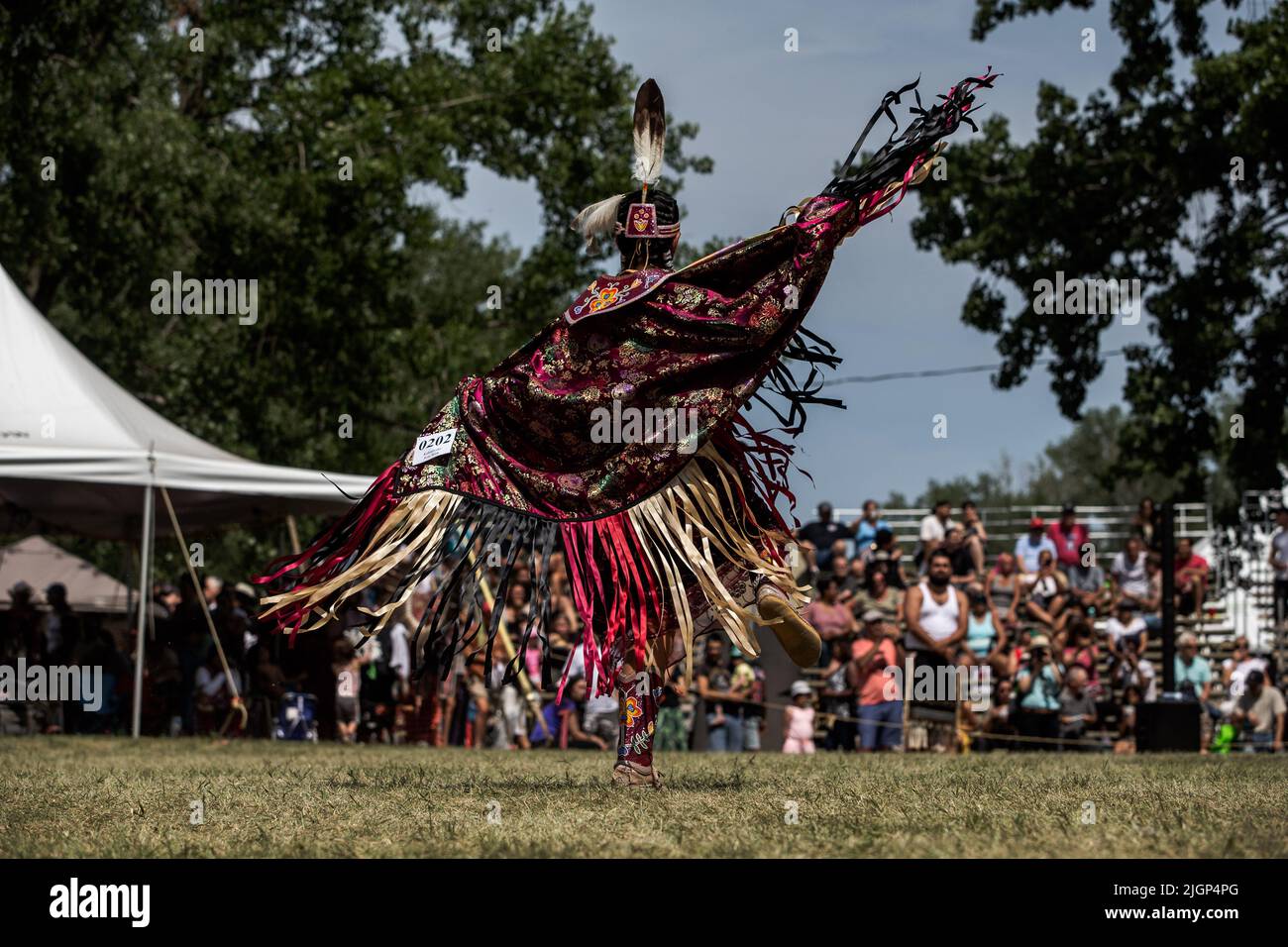 A pow-wow dancer doing a traditional dance in the arena during the ...