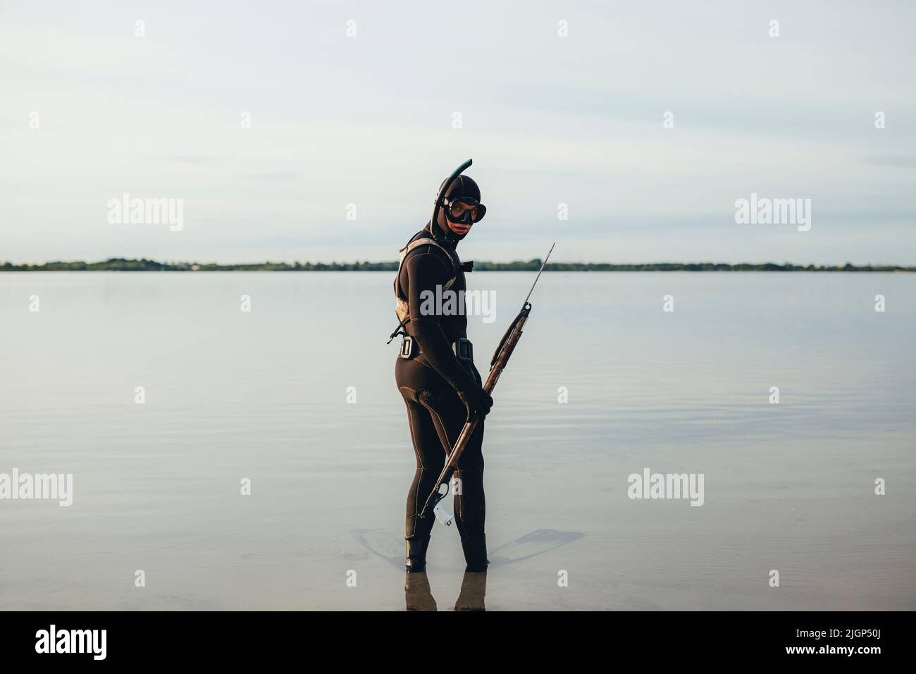 Rearview of spear fisherman standing in sea water with a speargun in ...