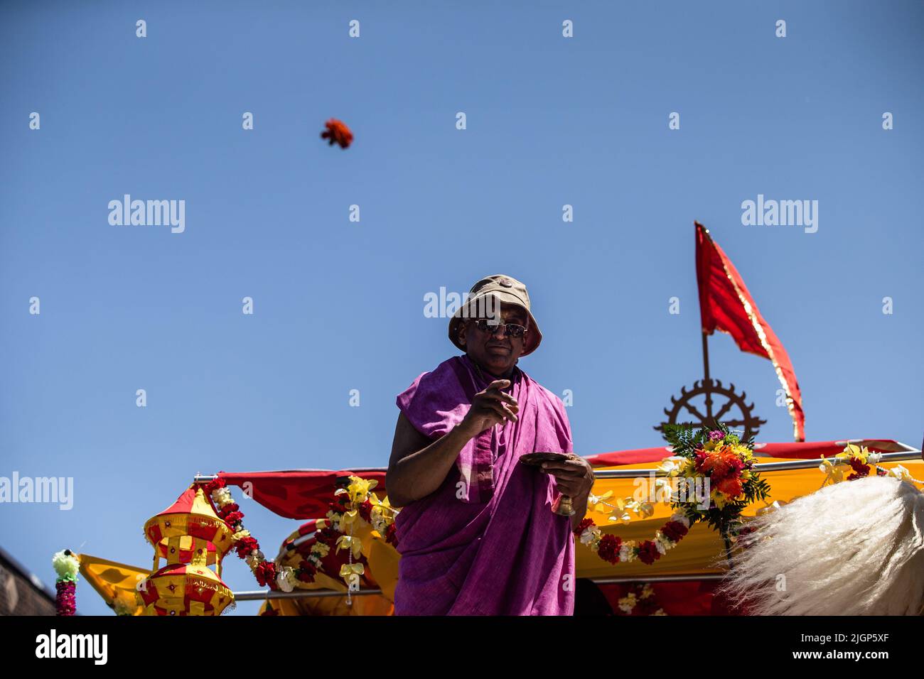 A devotee throws roses at the crowd from the main float cart during the ...