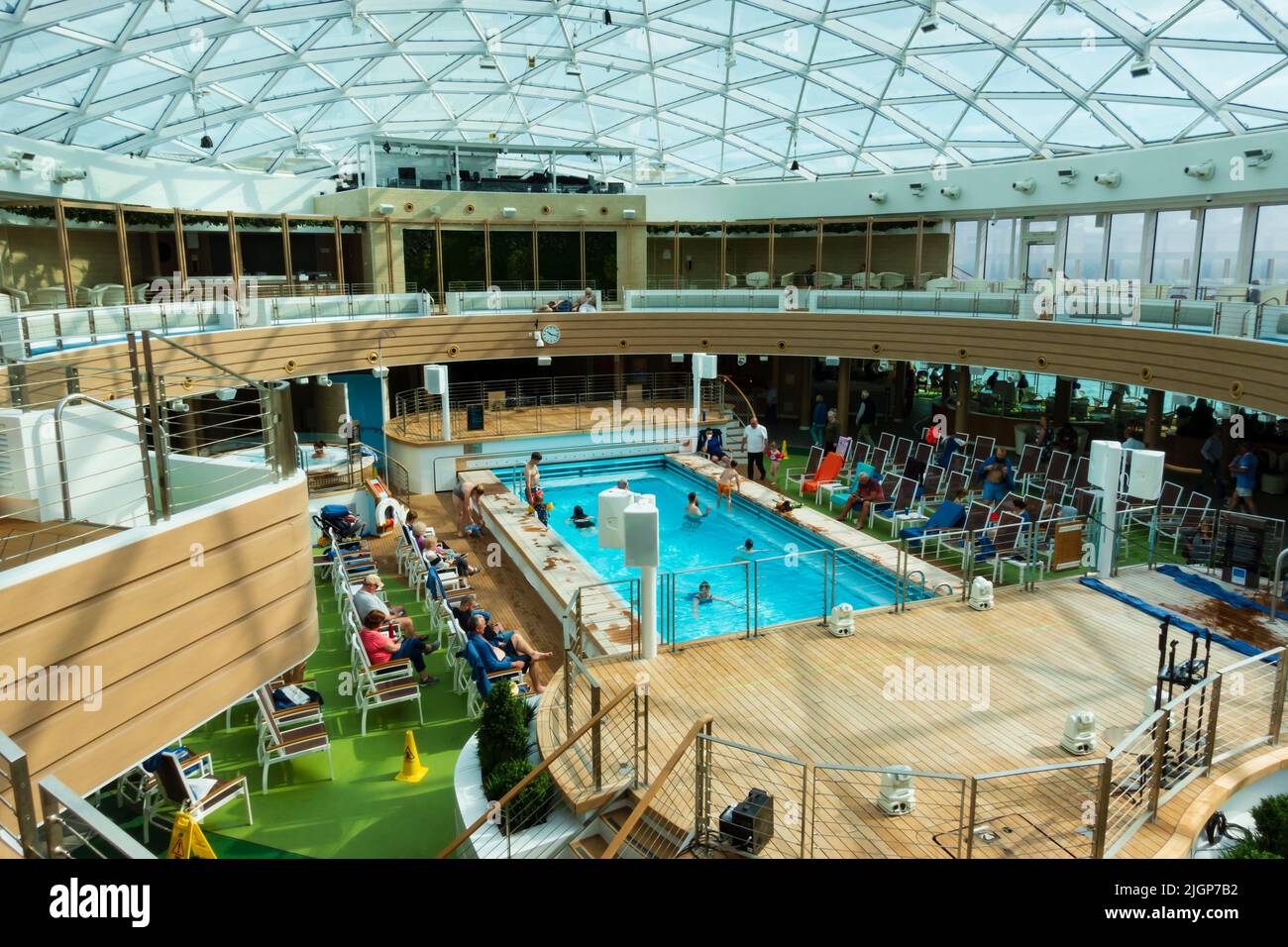 Passengers enjoy the pool and seating to relax under the Skydome on ...