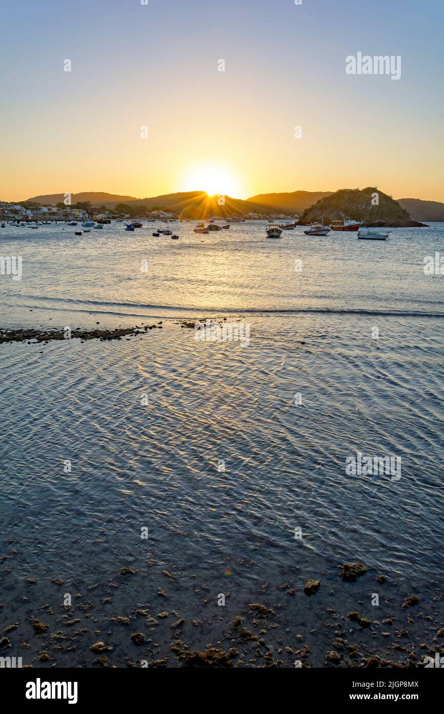 Sunset behind the hills and reflected in the sea waters of the city of ...