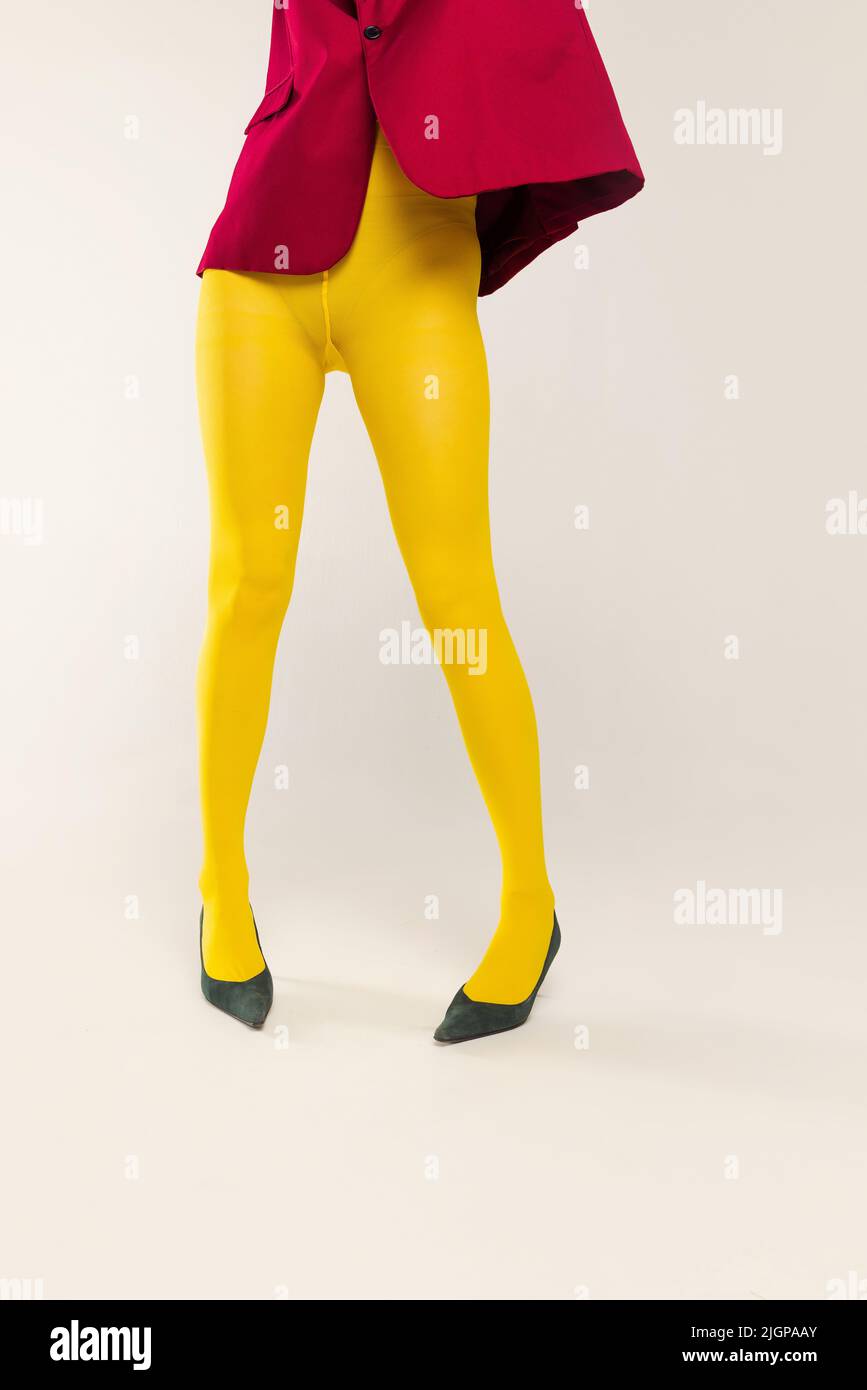 Cropped image of female legs in yellow bright tights and heels isolated ...