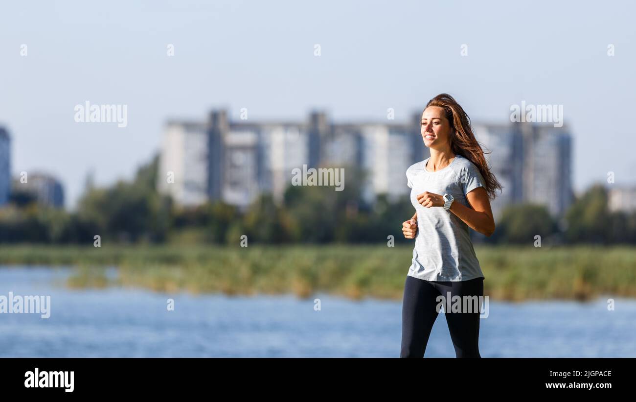 Young fitness woman running in the morning near the lake Stock Photo ...