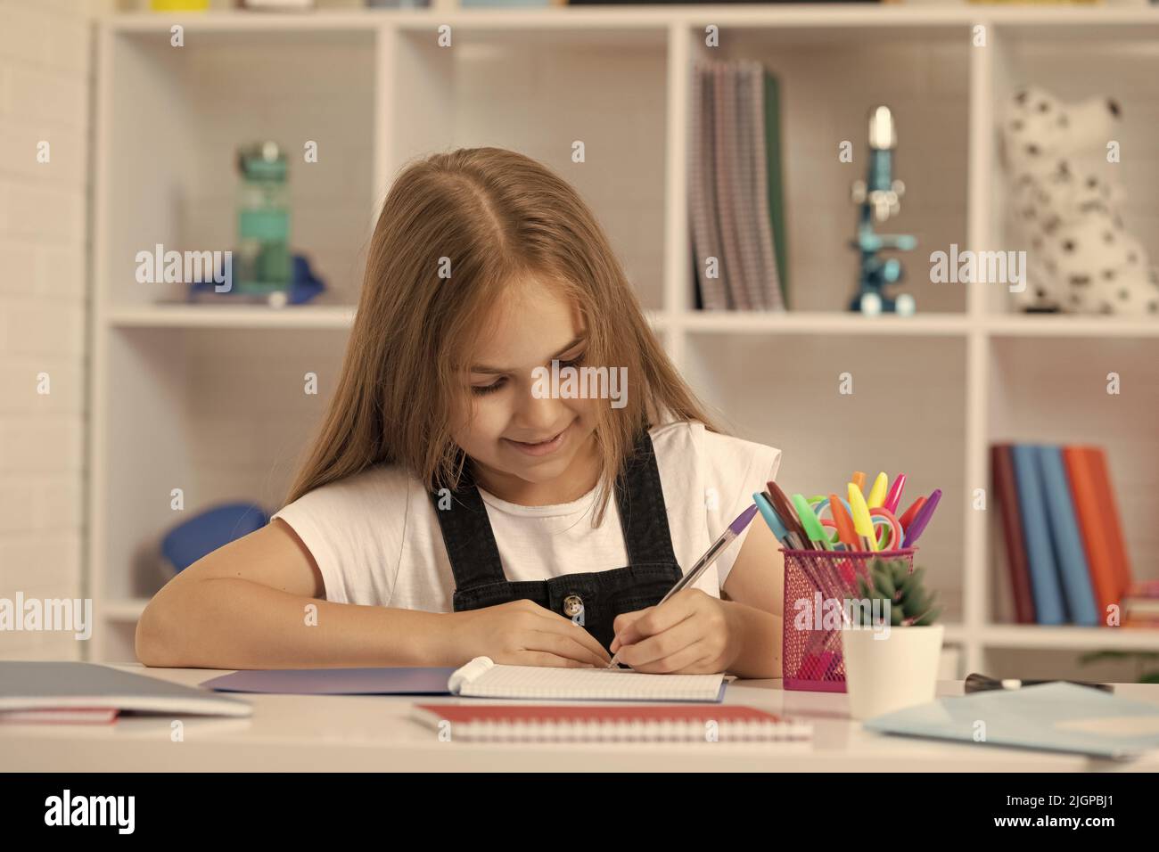 happy kid write in workbook at school lesson in classroom wear uniform ...