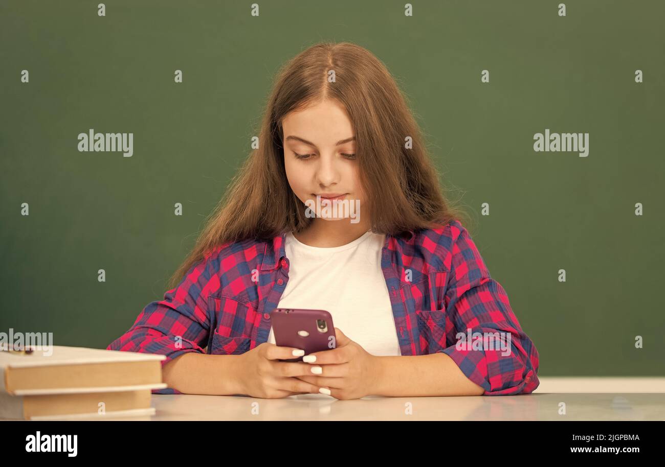 busy teen girl typing message on mobile phone in high school at ...