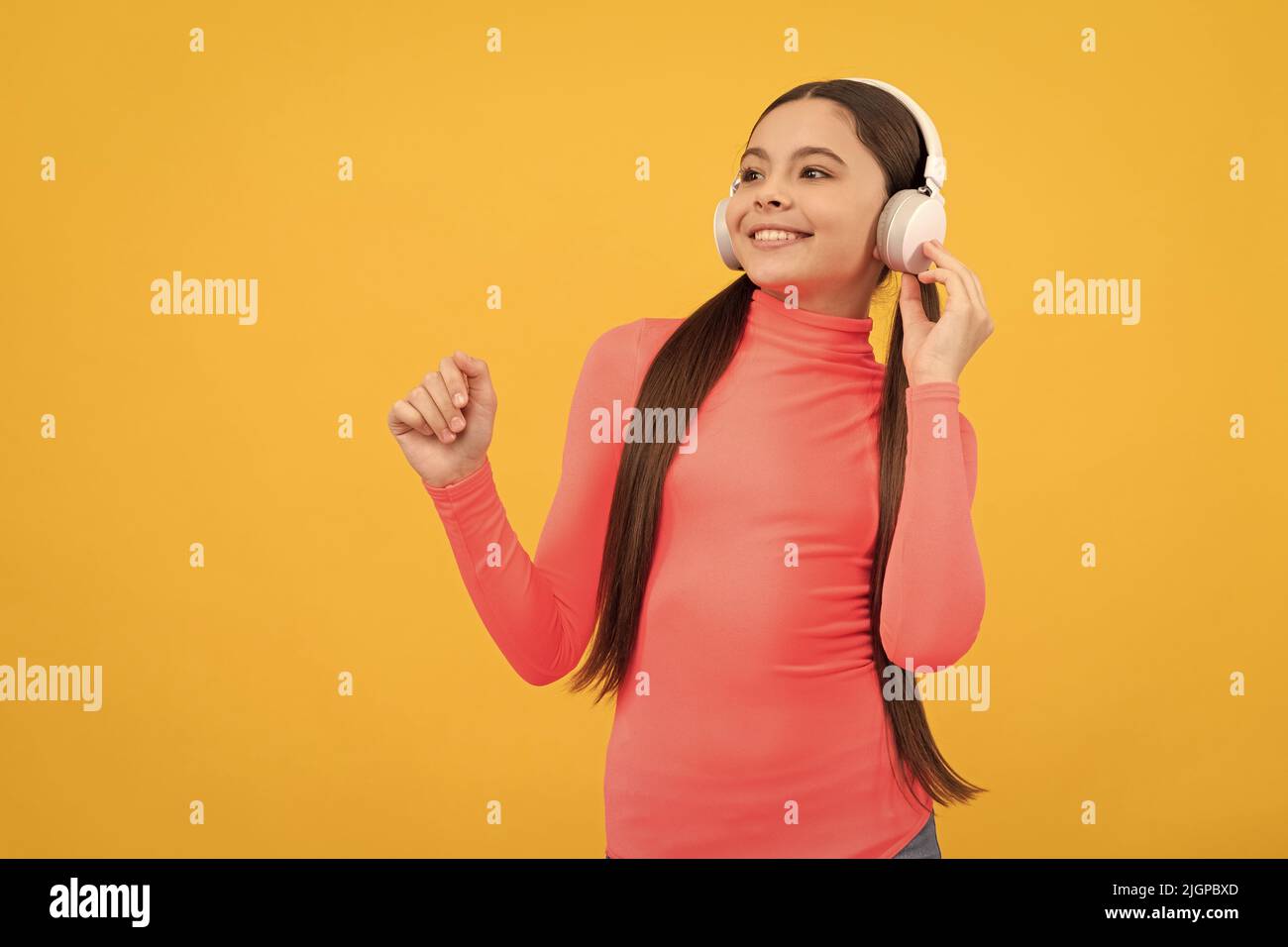 happy teen girl listen music in headphones on yellow background, copy ...
