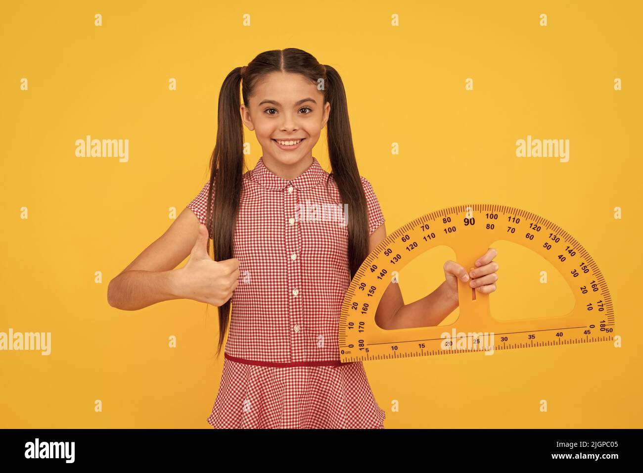 happy child hold school math tool protractor ruler on yellow background ...