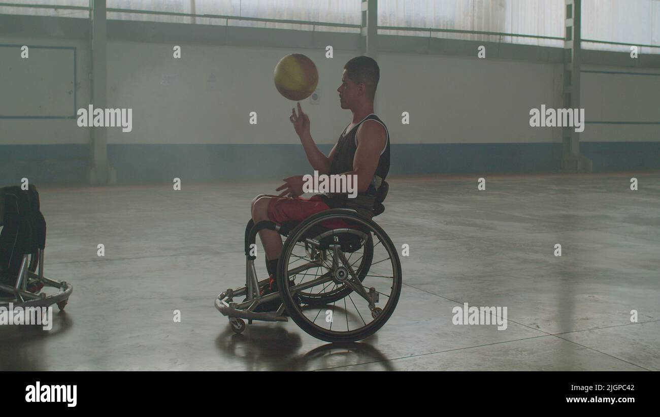 Two paraplegic athletes on wheelchair. A disabled athlete spinning ball ...