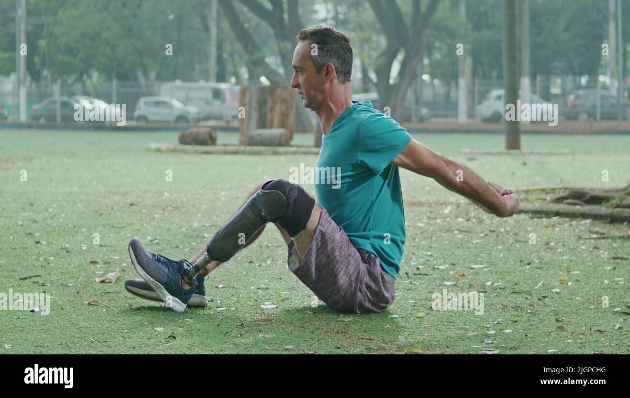 One disabled man with prosthetic leg stretching outside after sport ...