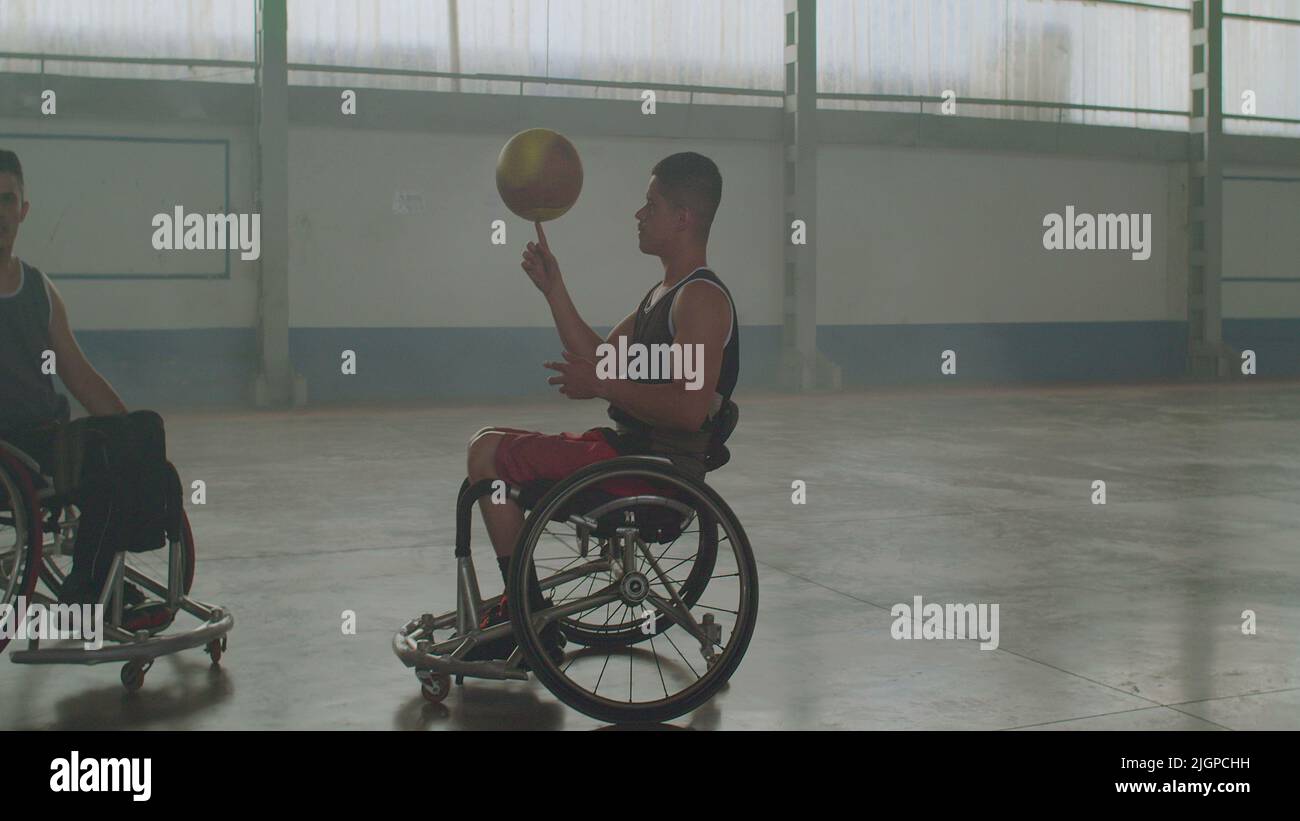 Two paraplegic athletes on wheelchair. A disabled athlete spinning ball ...