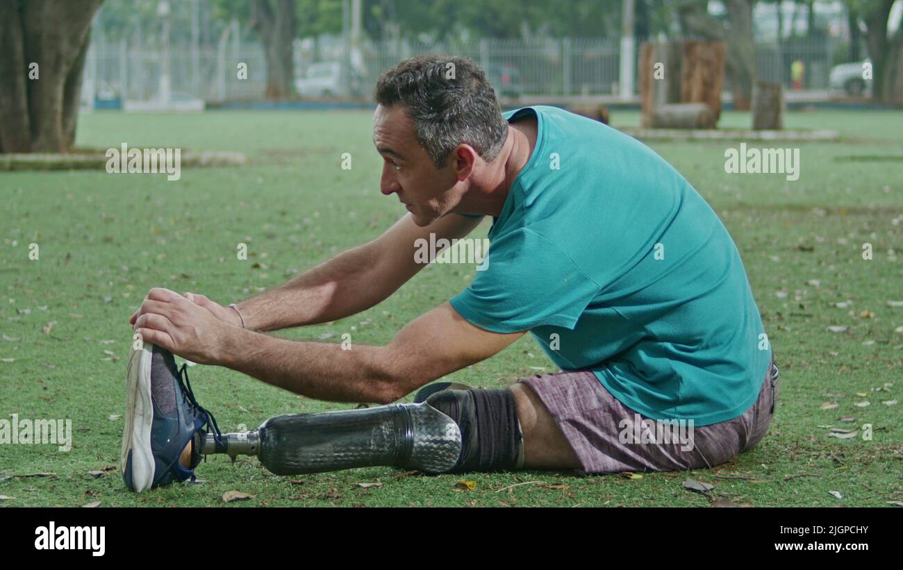 One disabled man with prosthetic leg stretching outside after sport ...