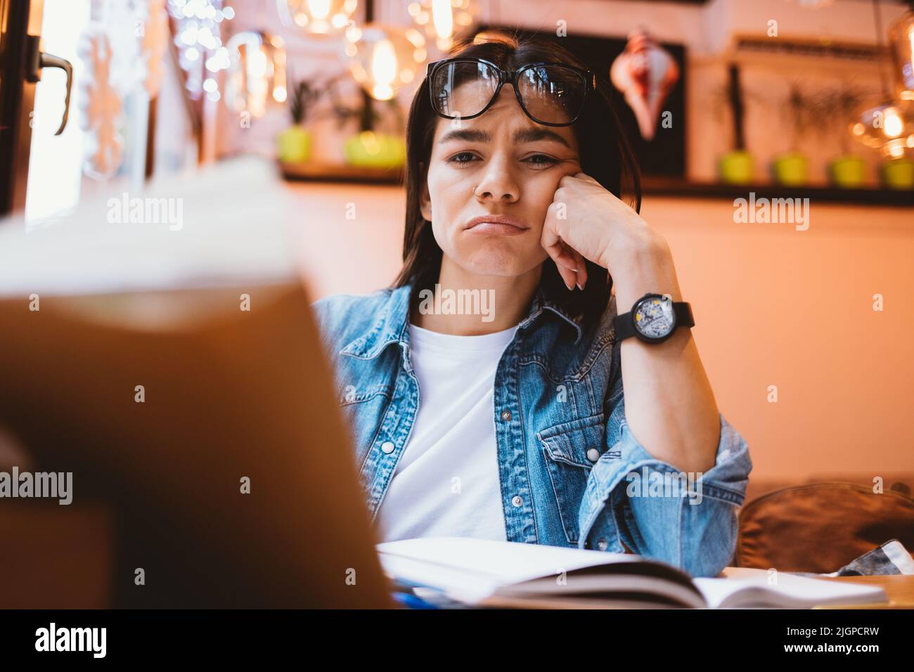 Bored female student sitting at the table with books, tired of studying ...