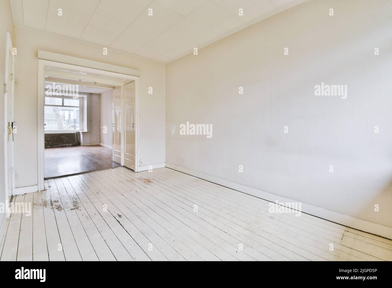 Plastic window and radiator on white wall in empty light room at home ...