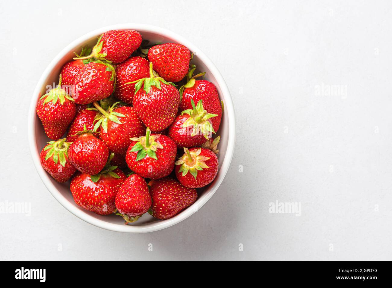 Fresh strawberries in a white bowl on a gray background Stock Photo - Alamy