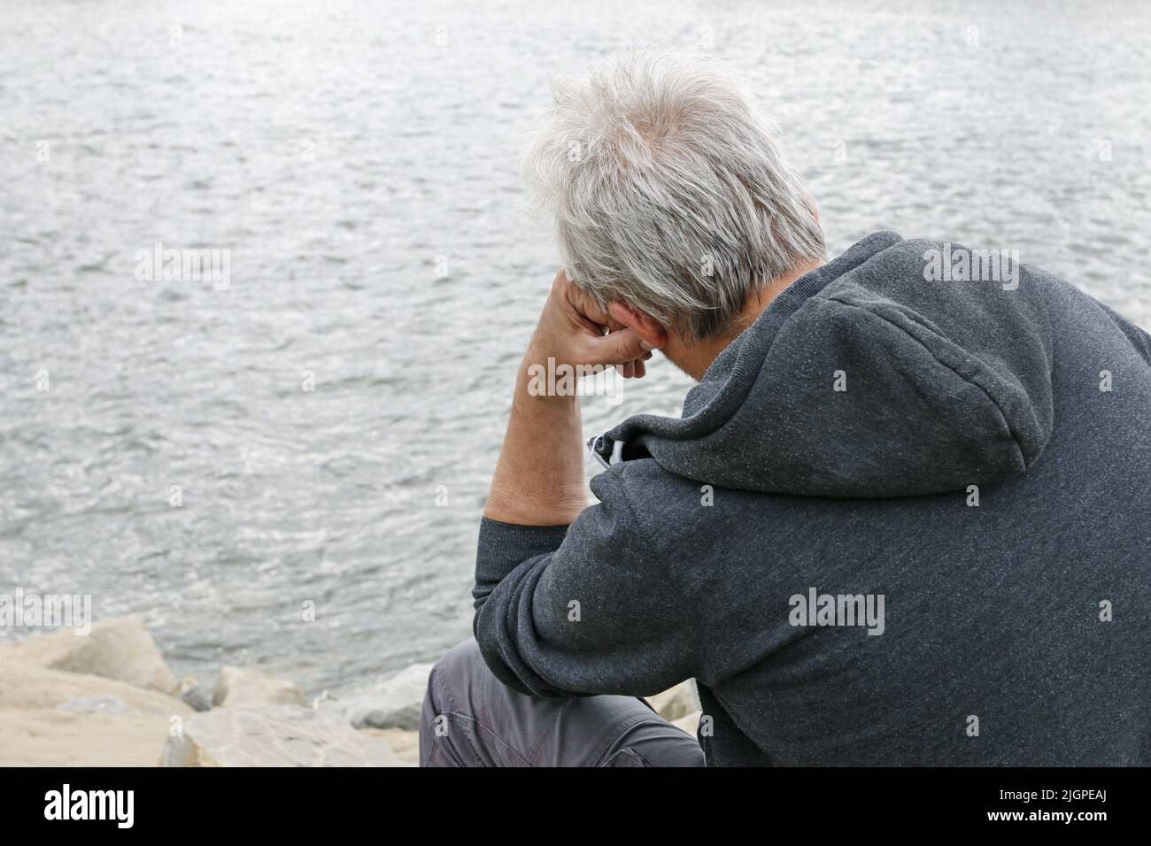 Sad man sitting on rocks hi-res stock photography and images - Alamy