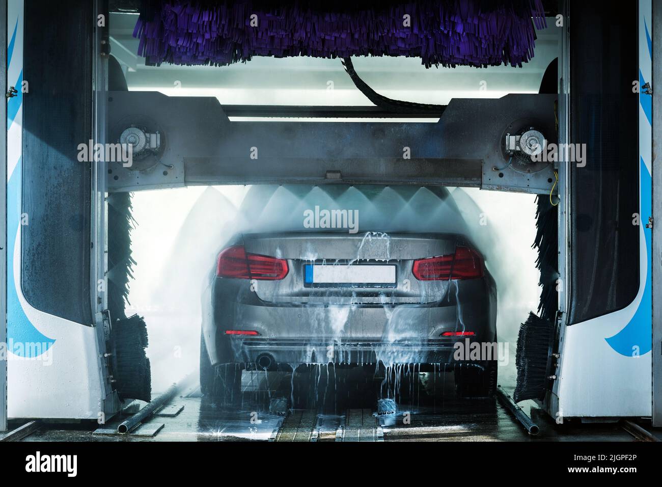 A grey business sedan vehicle running through an automatic car wash ...