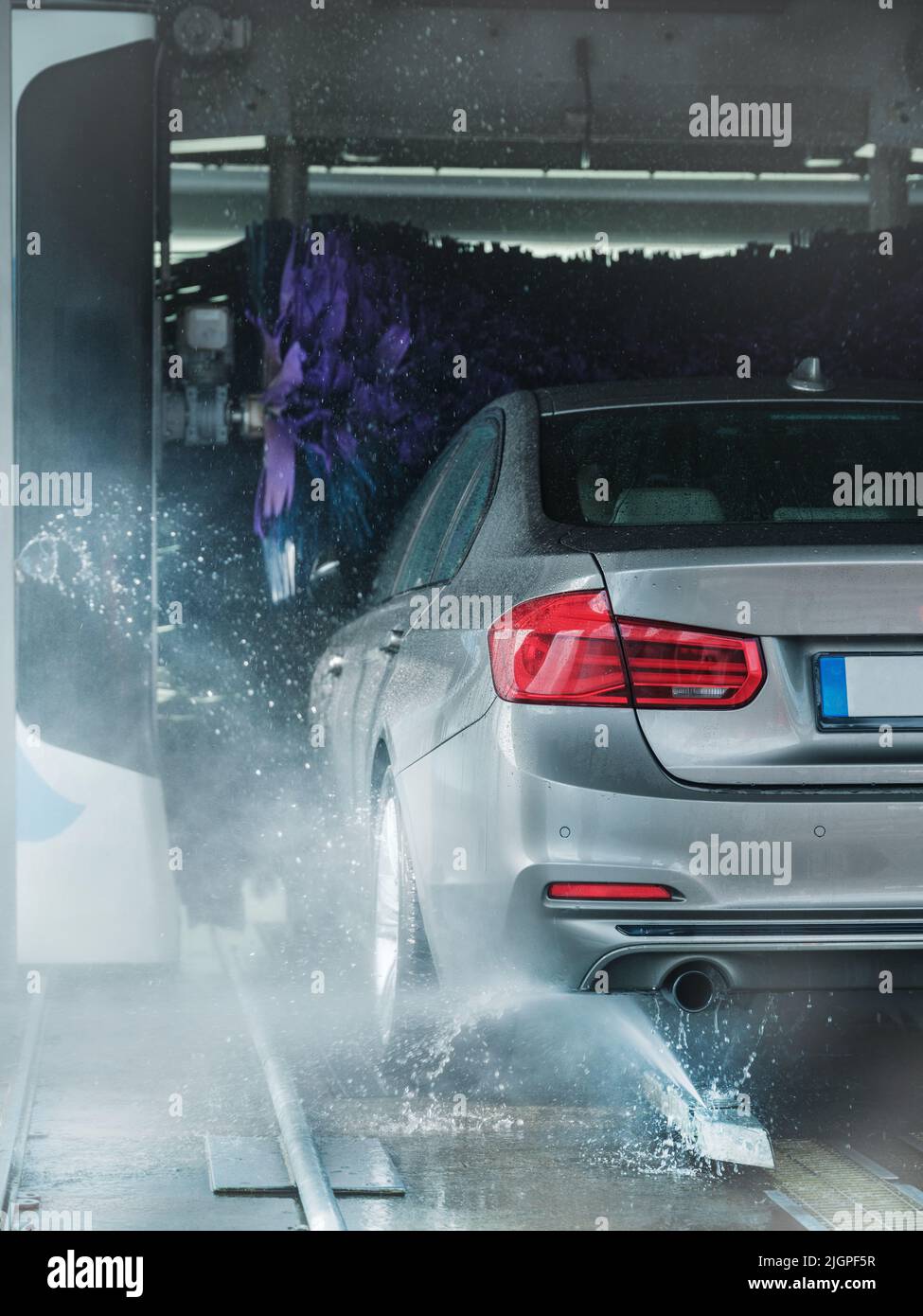 A grey business sedan vehicle running through an automatic car wash ...