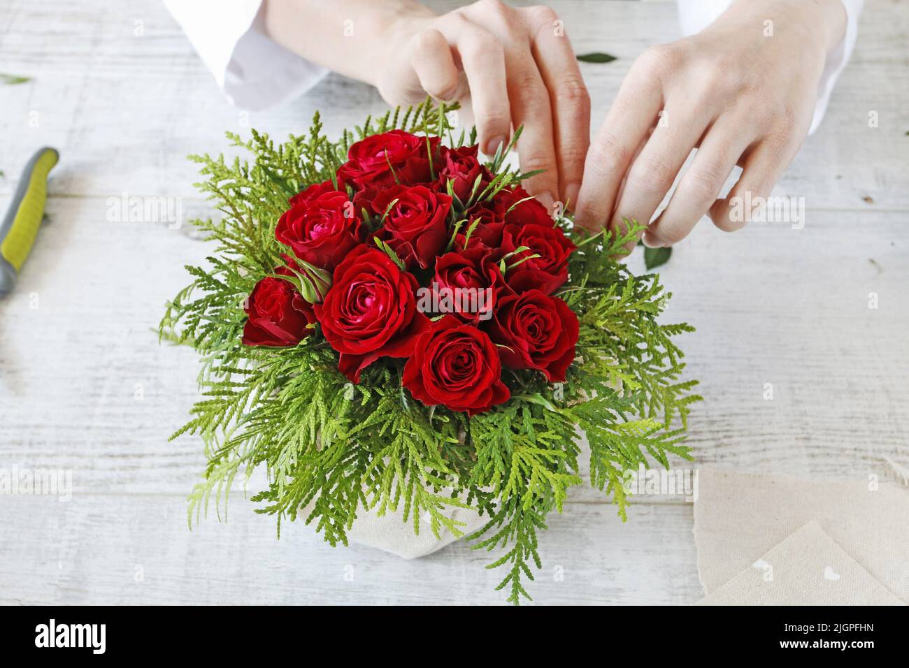 Florist at work: Woman shows how to make a floral arrangement with red ...
