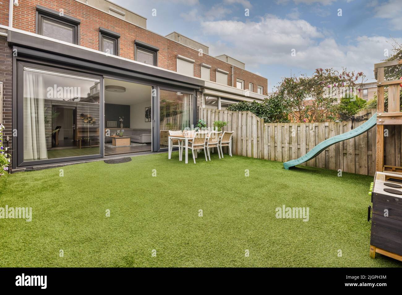 Neat paved patio with sitting area and small garden near wooden fence ...