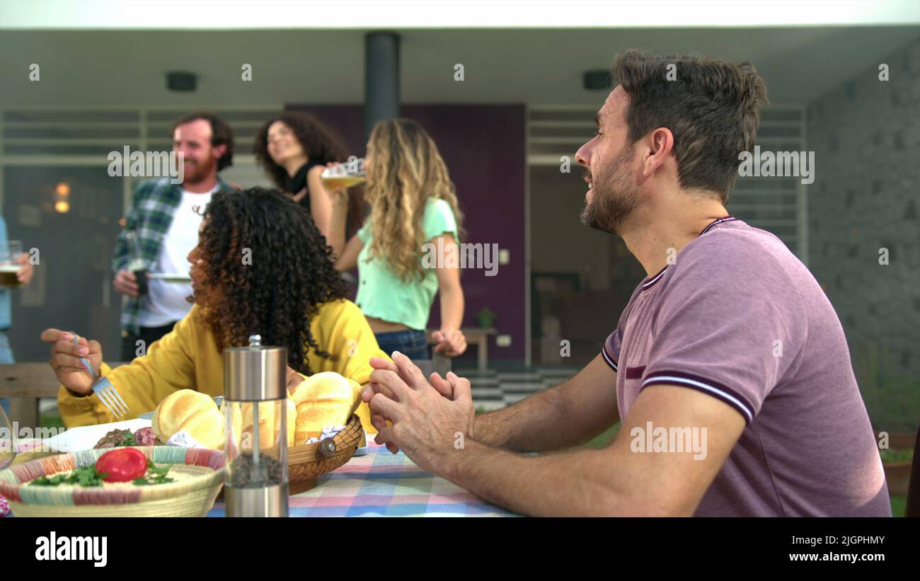 Friends having barbecue. BBQ Chef bringing corn. People gathered ...