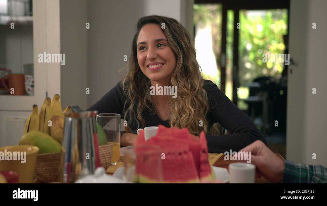 Happy girl in conversation with family members at breakfast table in ...