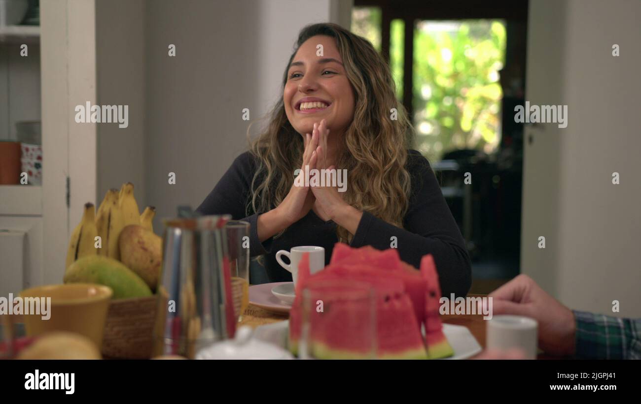Happy girl in conversation with family members at breakfast table in ...