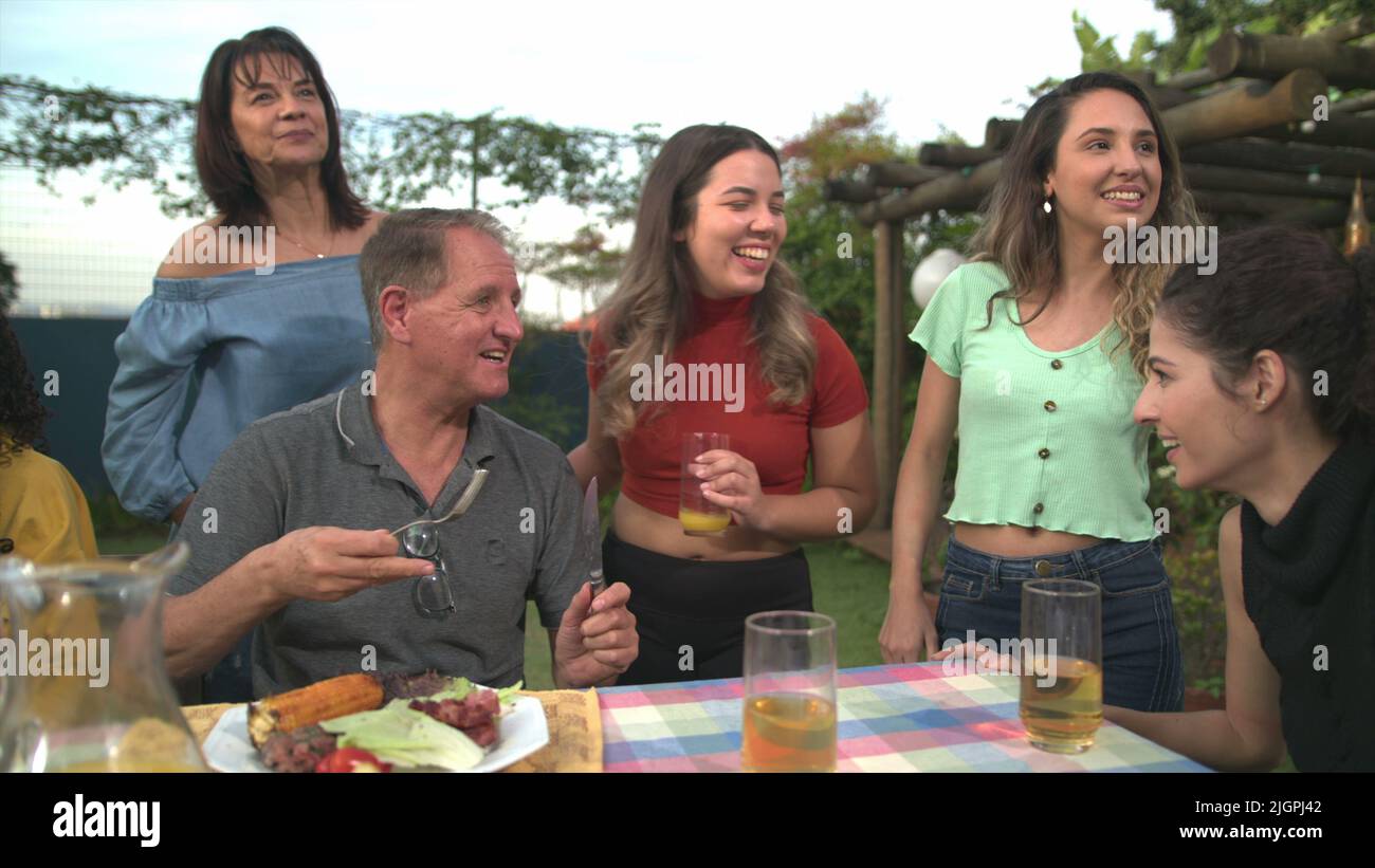 Group of cheerful friends eating barbecue together. BBQ chef serving ...