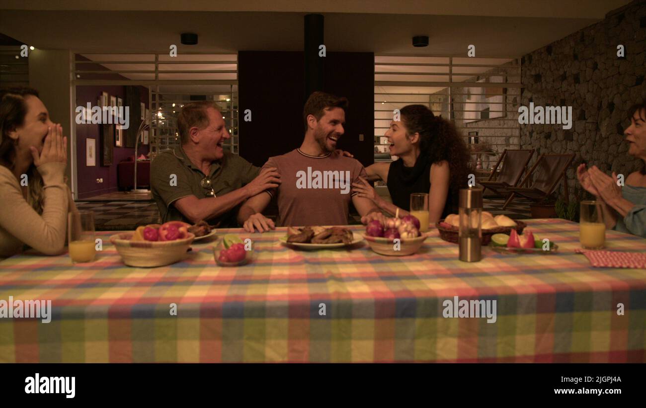 Man giving positive news to family during backyard dinner. Group of ...