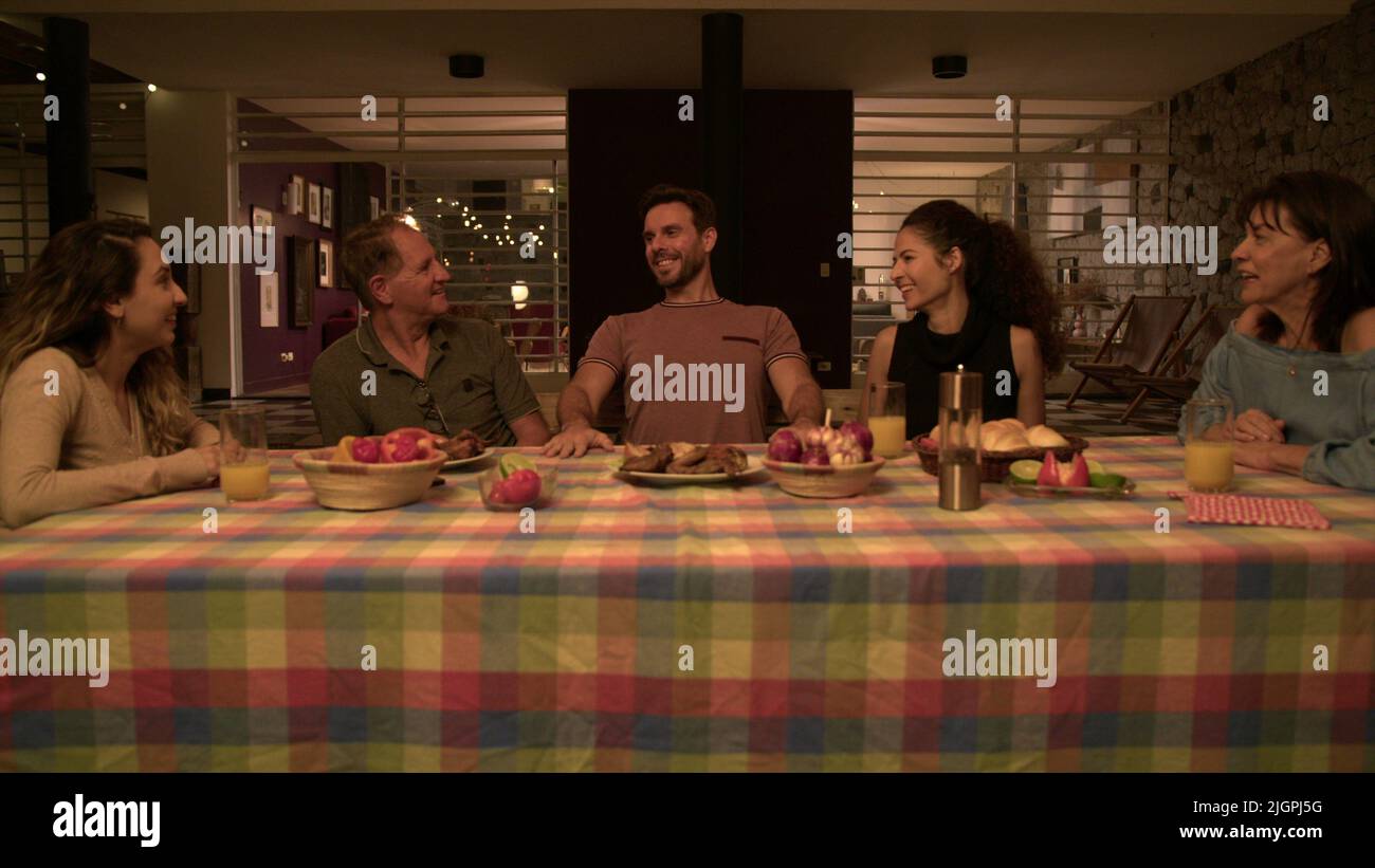 Man giving positive news to family during backyard dinner. Group of ...