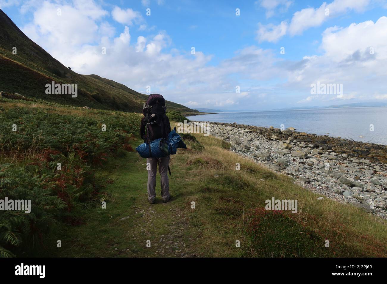Solo Backpacker hiking with a big backpack. Arran Coastal Way. Isle of ...