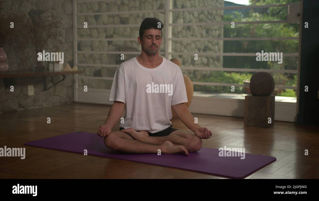 Concentrated person meditating at home on his living room floor sitting ...