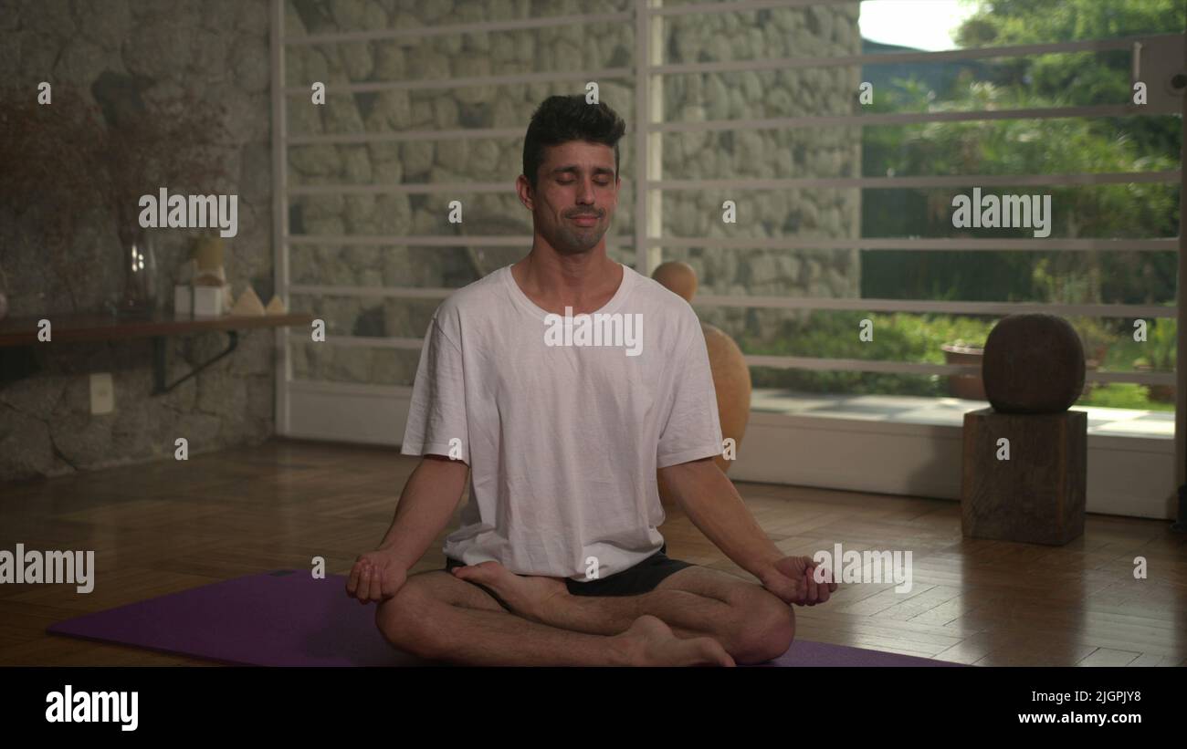 Concentrated person meditating at home on his living room floor sitting ...